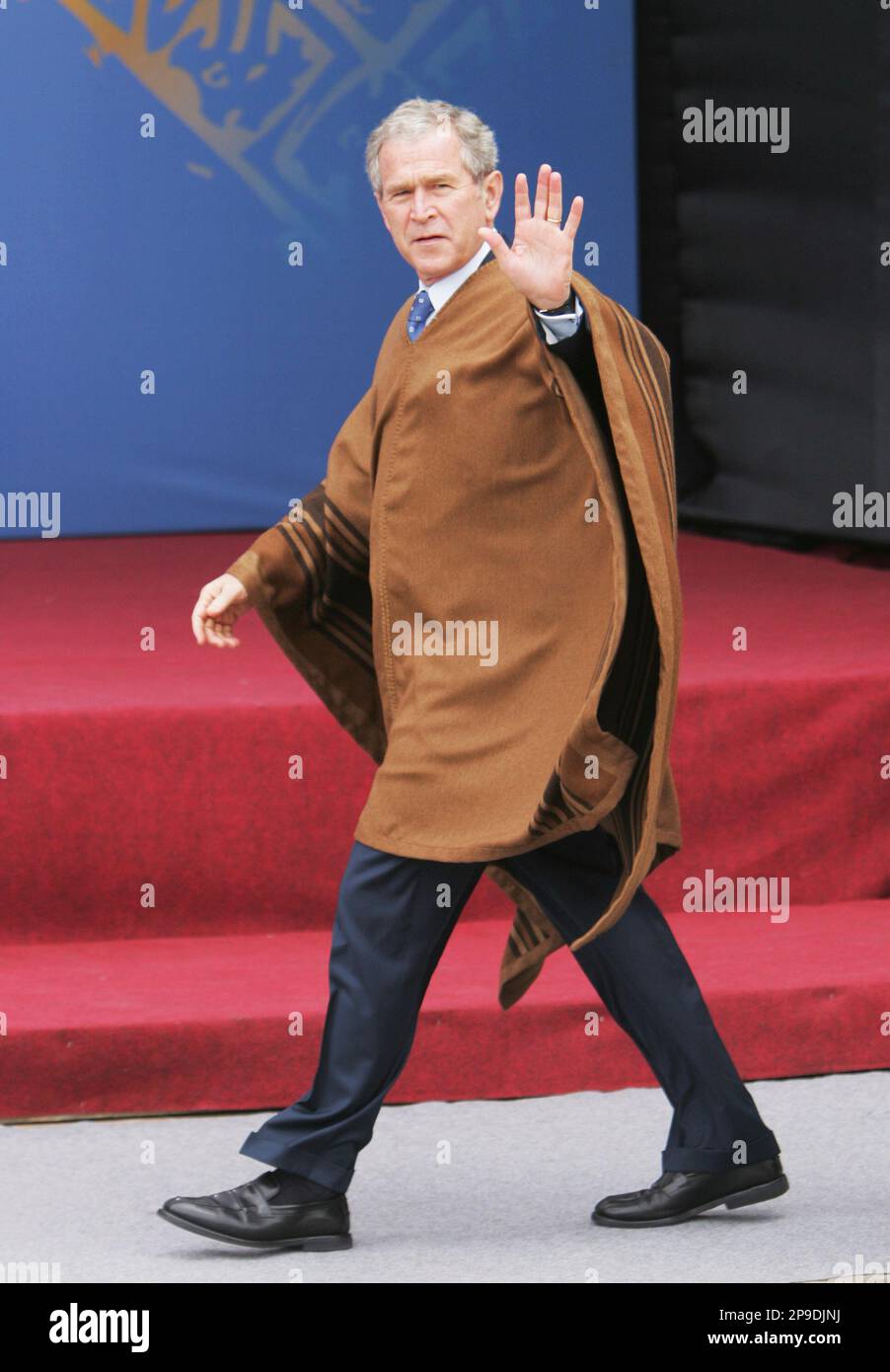 President George W. Bush, wearing a traditional Peruvian poncho, waves ...