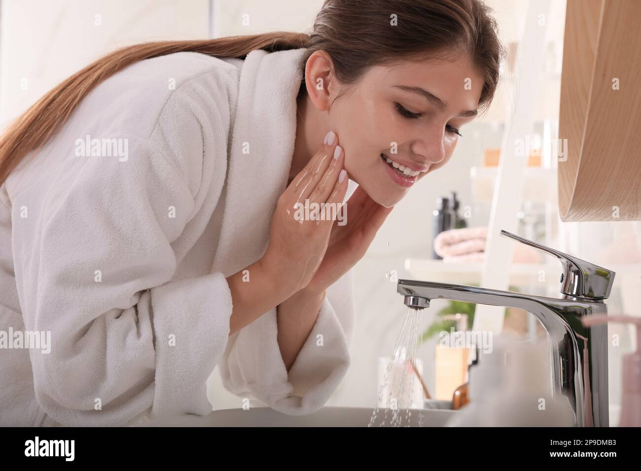 Beautiful teenage girl washing face with water in bathroom Stock Photo ...