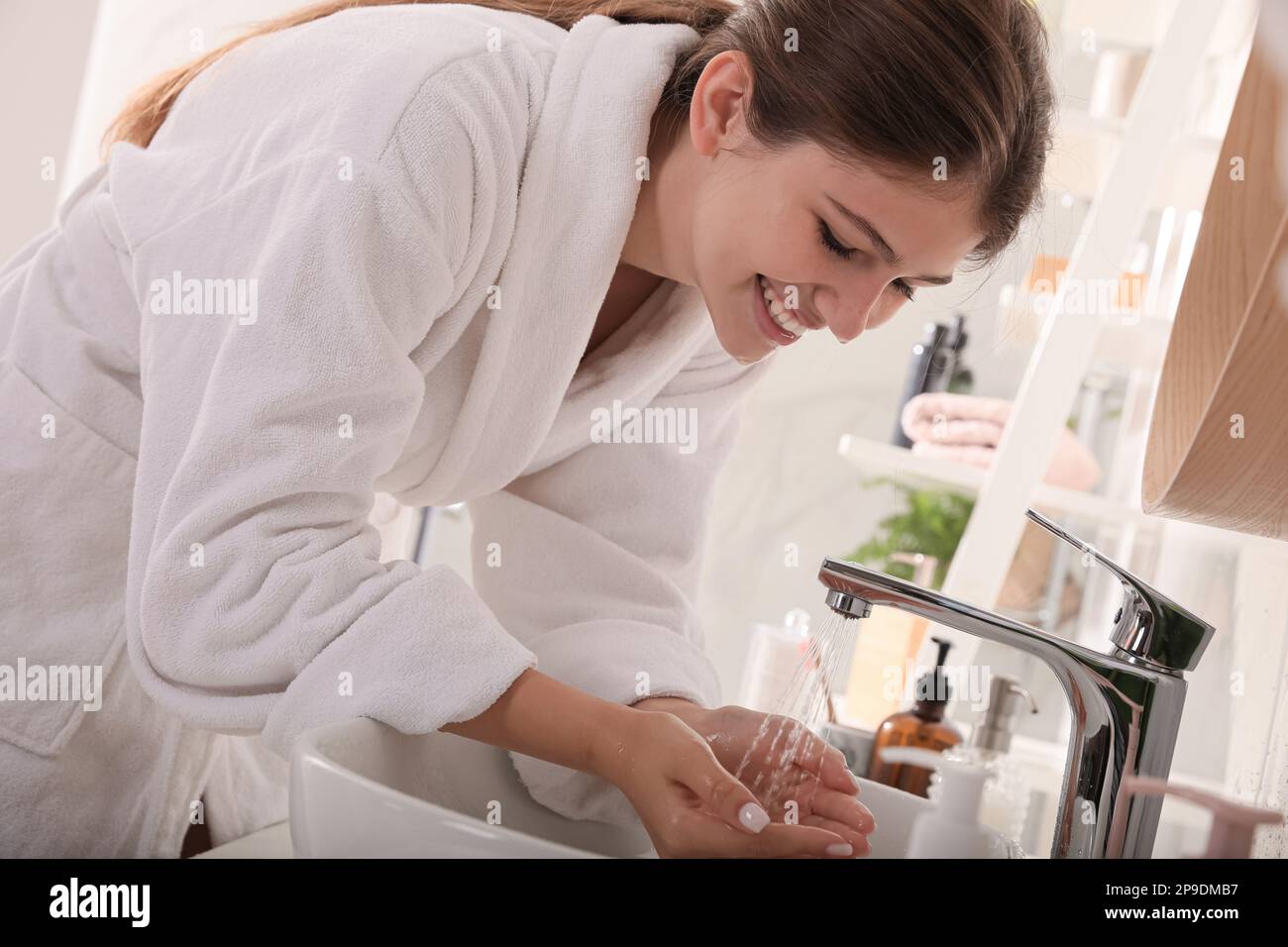 Beautiful teenage girl washing face with water in bathroom Stock Photo ...