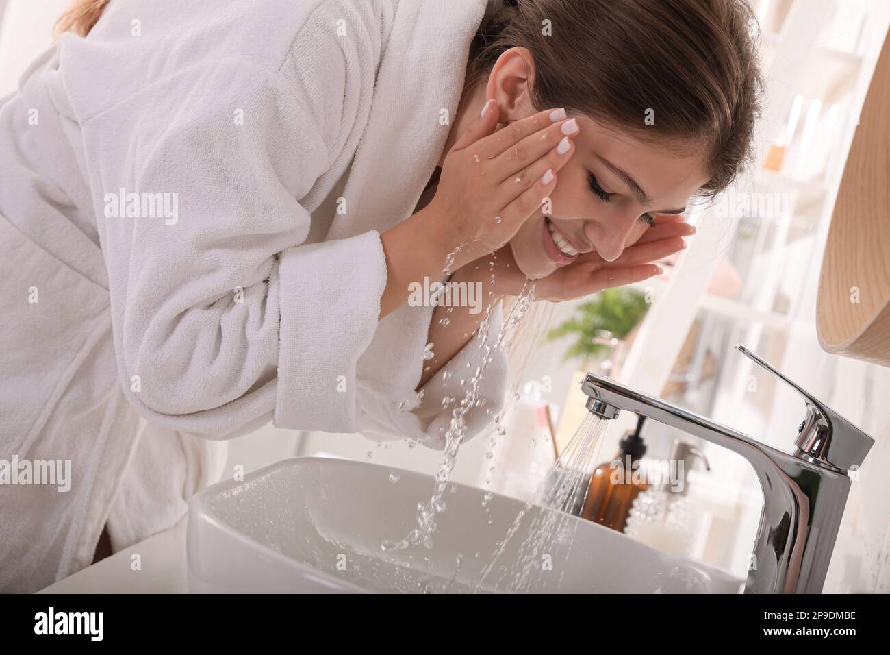 Beautiful teenage girl washing face with water in bathroom Stock Photo ...