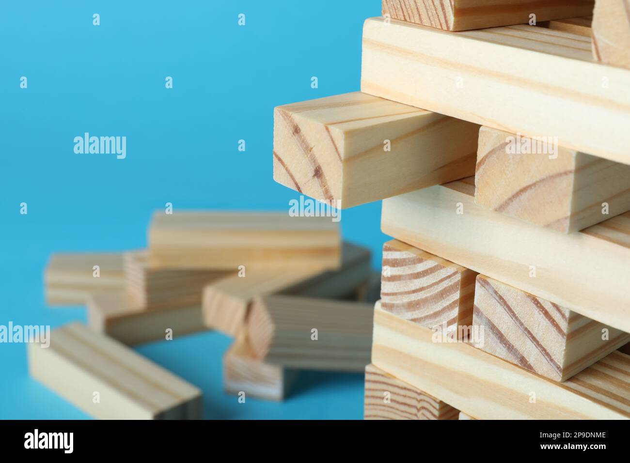 Jenga tower made of wooden blocks on light blue background, closeup ...
