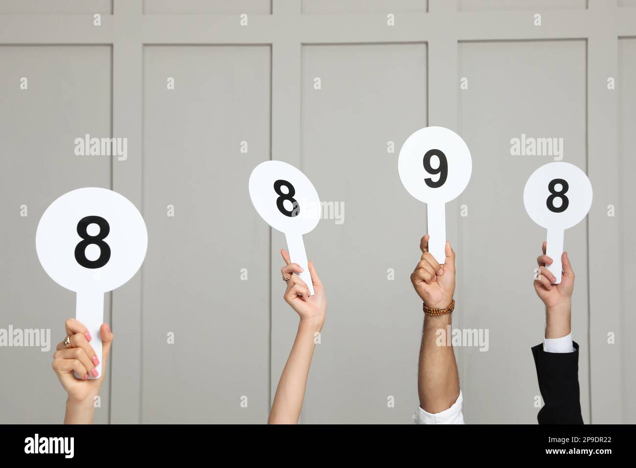 Panel of judges holding different score signs against light wall ...