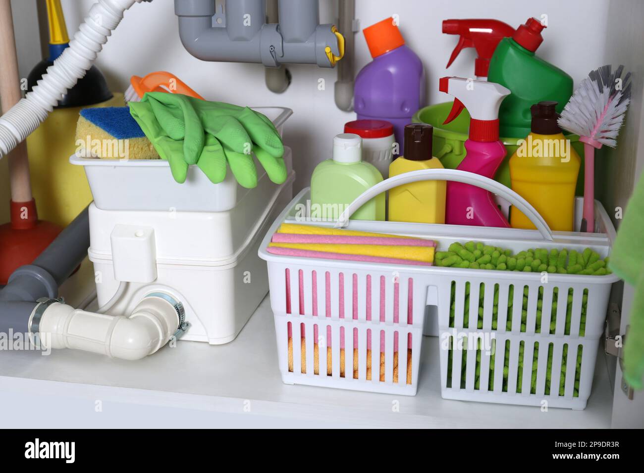 Open under sink cabinet with different cleaning supplies in kitchen ...