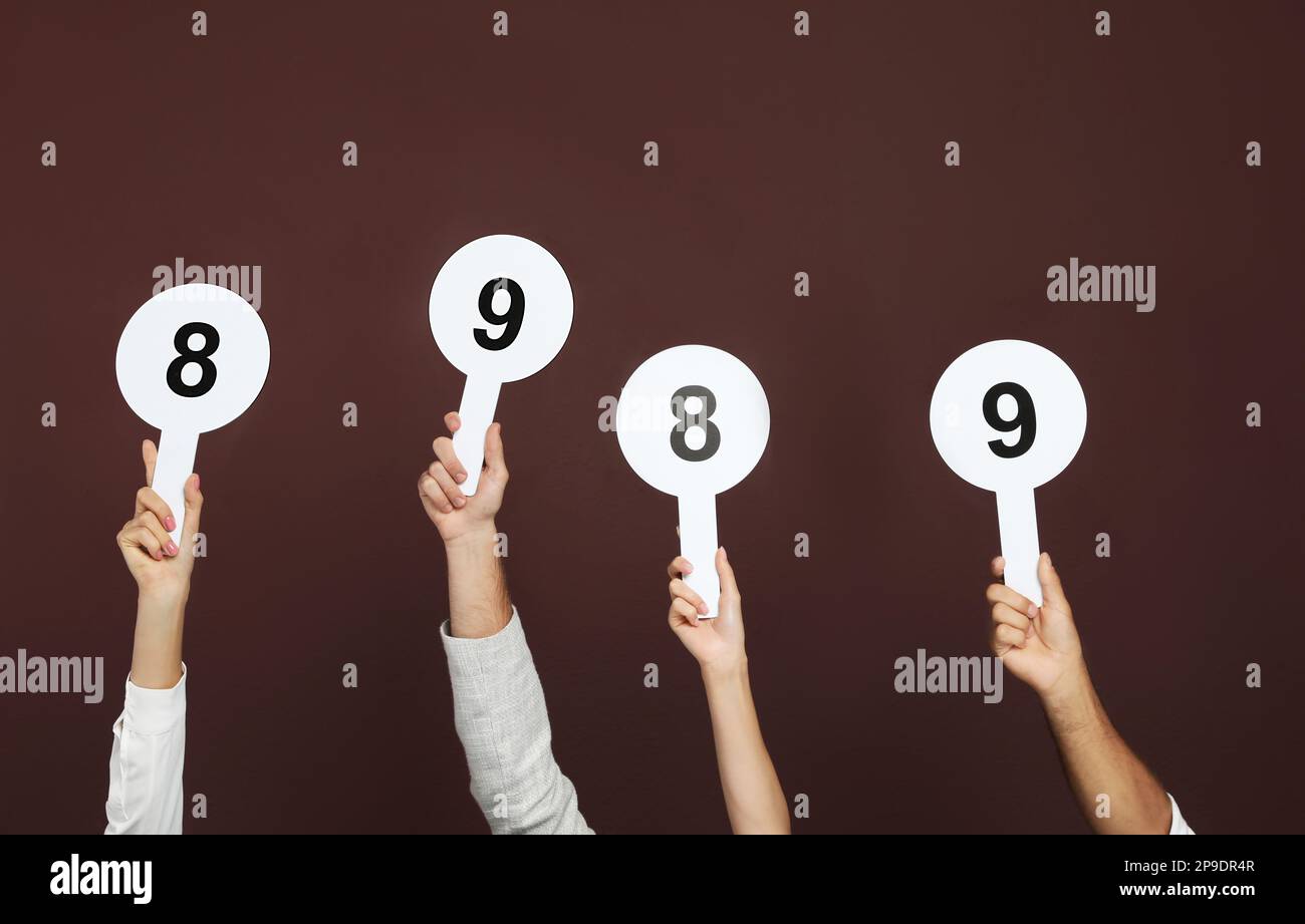 Panel of judges holding different score signs on brown background ...