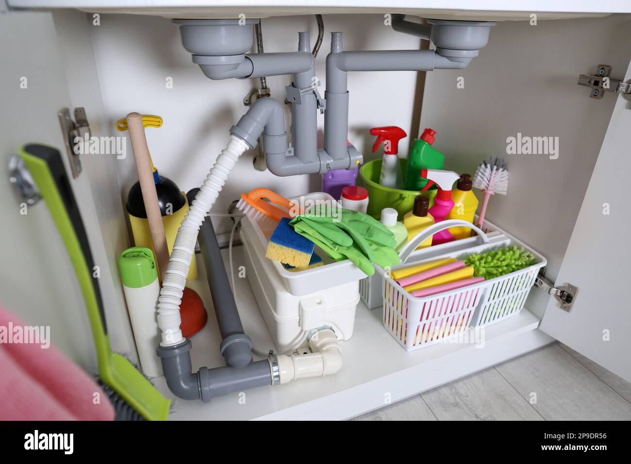 Open under sink cabinet with different cleaning supplies in kitchen ...