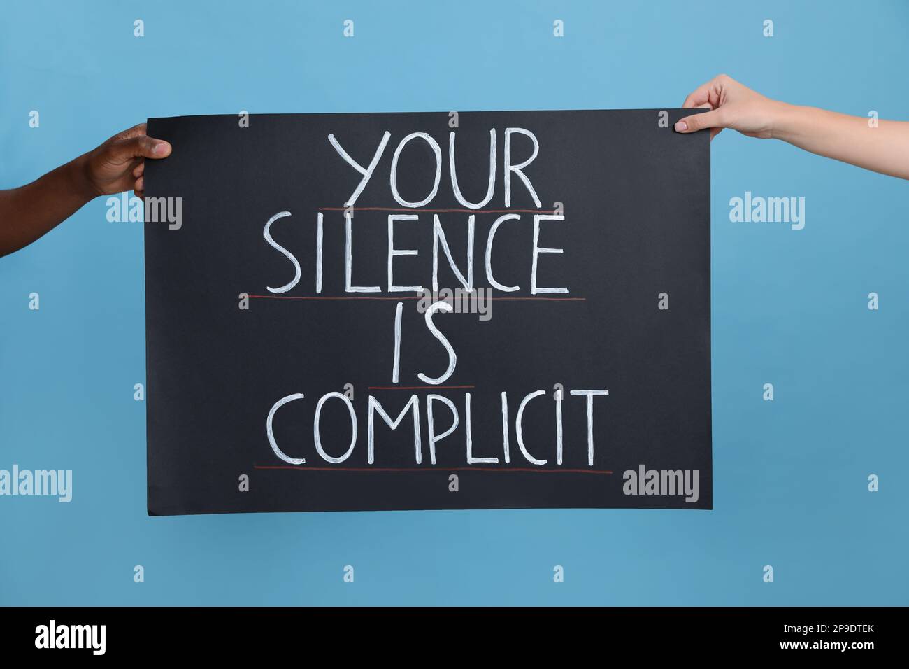Woman and African American man holding sign with phrase Your Silence Is ...