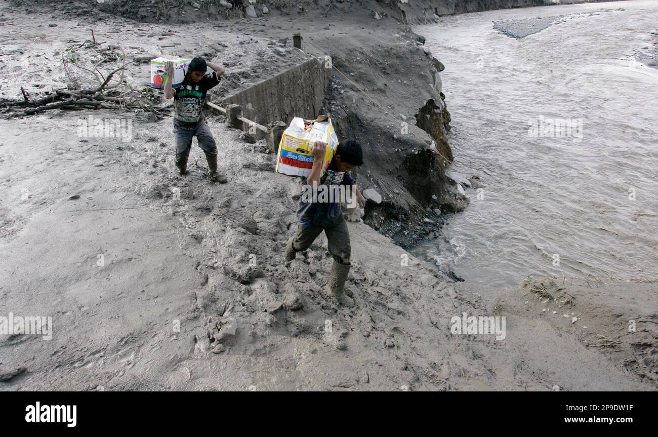 People walk along a road covered in mud after a landslide was triggered ...