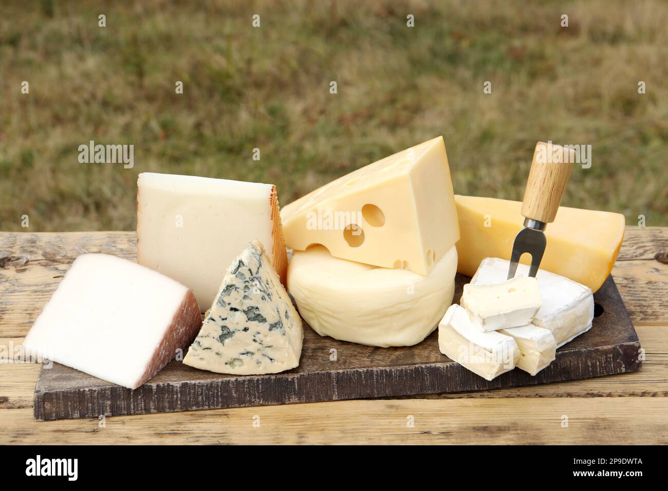 Different types of delicious cheeses on wooden table outdoors Stock ...