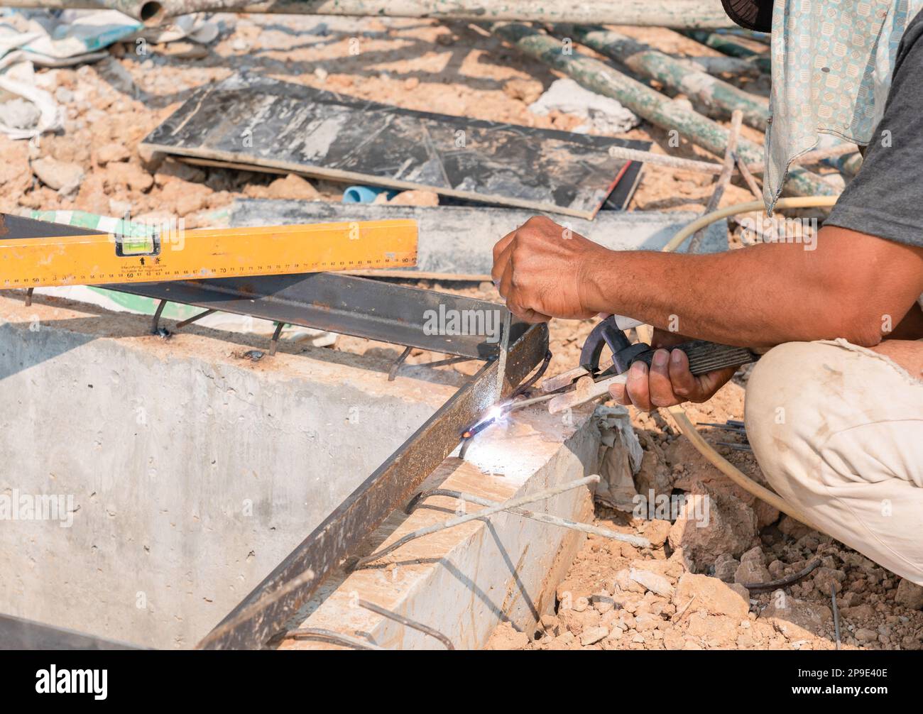 Worker welding formwork on edge of drain pond in construction site ...