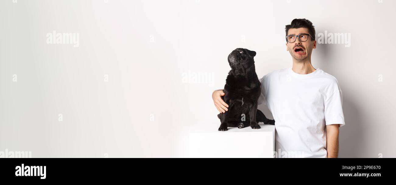 Whining man looking sad while pug staring intrigued at upper left ...