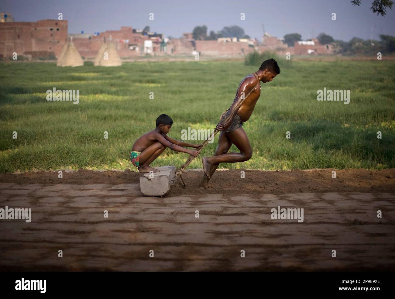 Pakistani Kushti wrestlers prepare the soil in the ring prior to a ...
