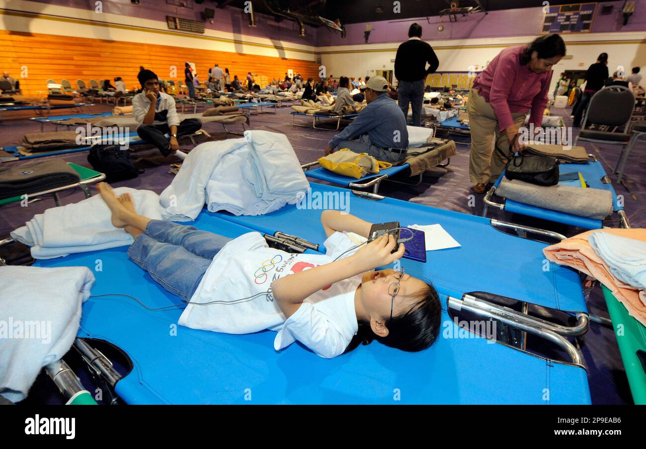 Grace Kim, 10, plays a video game as she lays on a cot in an evacuation ...
