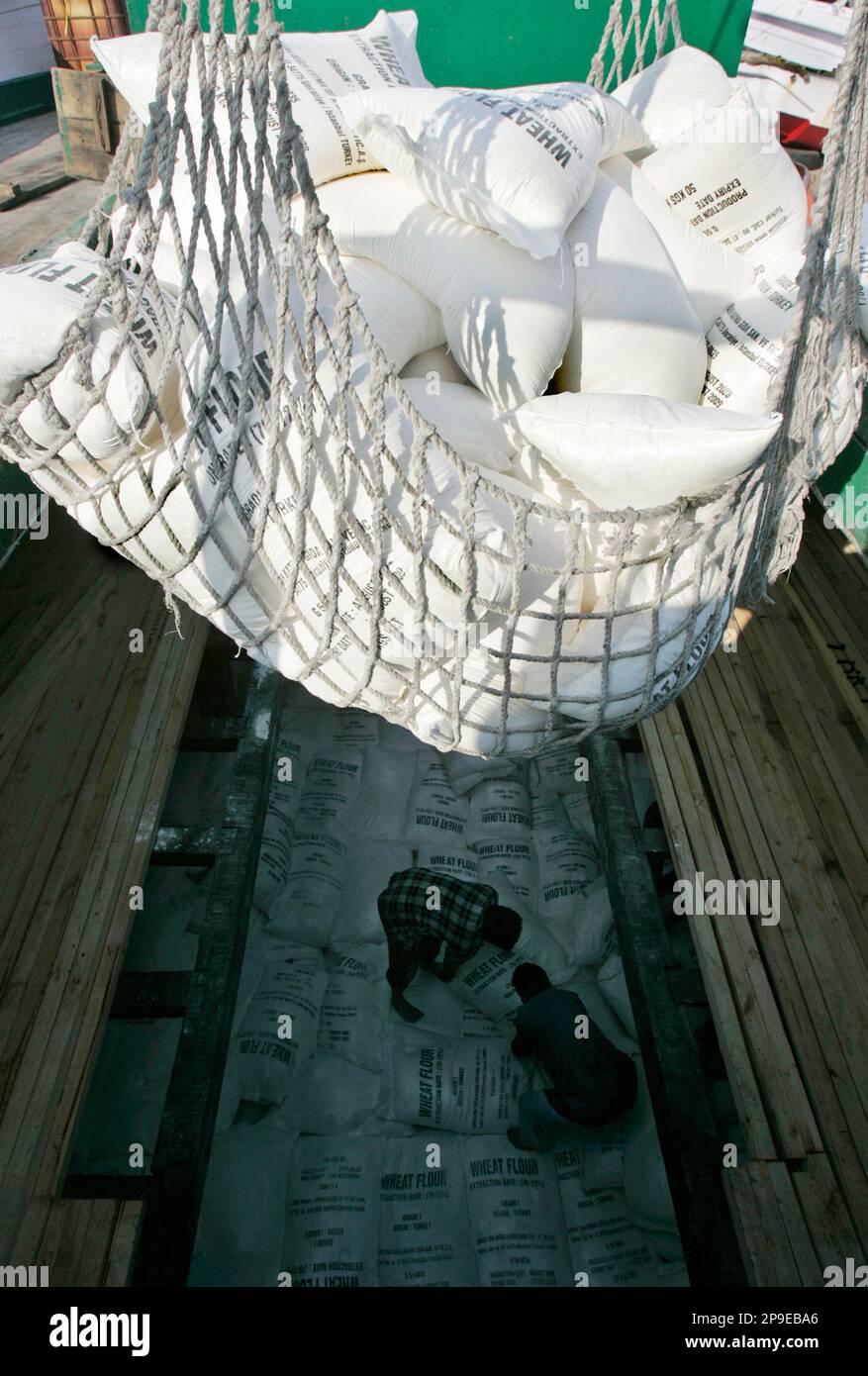 Workers load bags of wheat flour from Turkey into the hold of a ship as ...