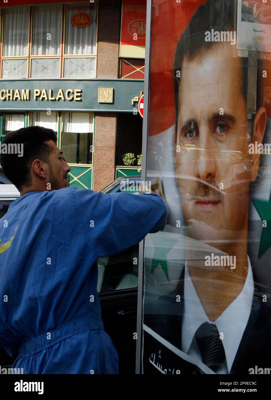 A Syrian worker cleans the glass of Syrian President Bashar Assad’s ...