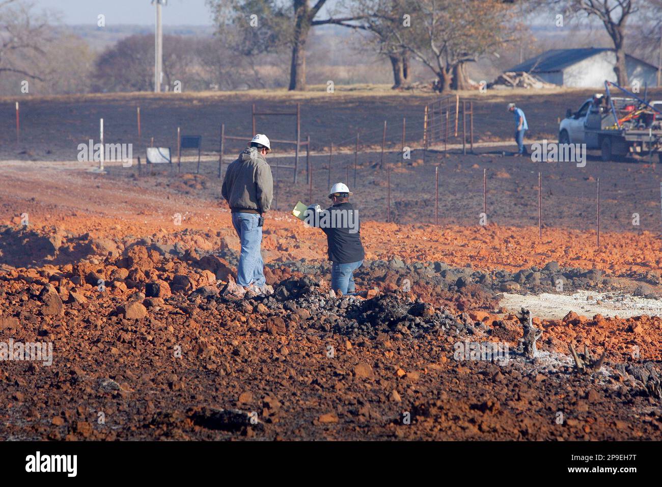 Workers examine and take photos of the crater from natural gas line ...