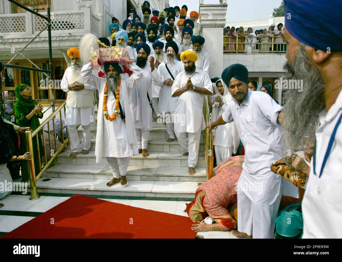A Sikh woman, right, bows in front of a Sikh priest as he carries the ...