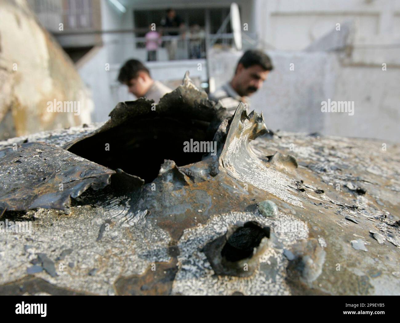 Iraqi civilians inspect a damaged car after a bomb explosion in Baghdad ...