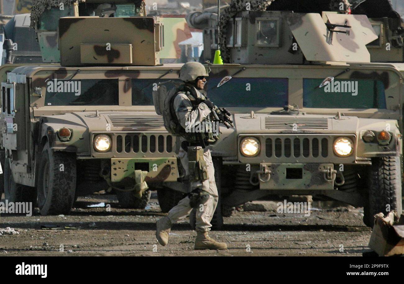 An Iraqi army soldier walks in front of Iraqi army vehicles at the ...