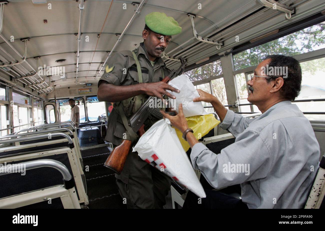 A Sri Lankan army soldier checks a commuter's belongings at a roadside checkpoint in Colombo ...
