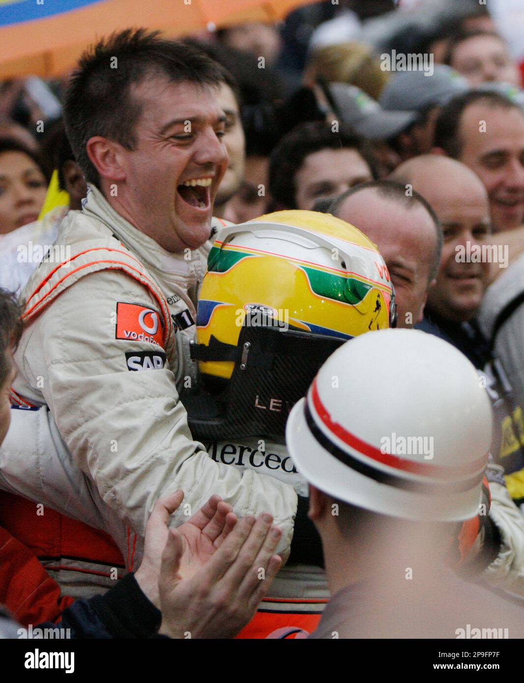 A mechanic of McLaren-Mercedes embraces driver Lewis Hamilton, of ...
