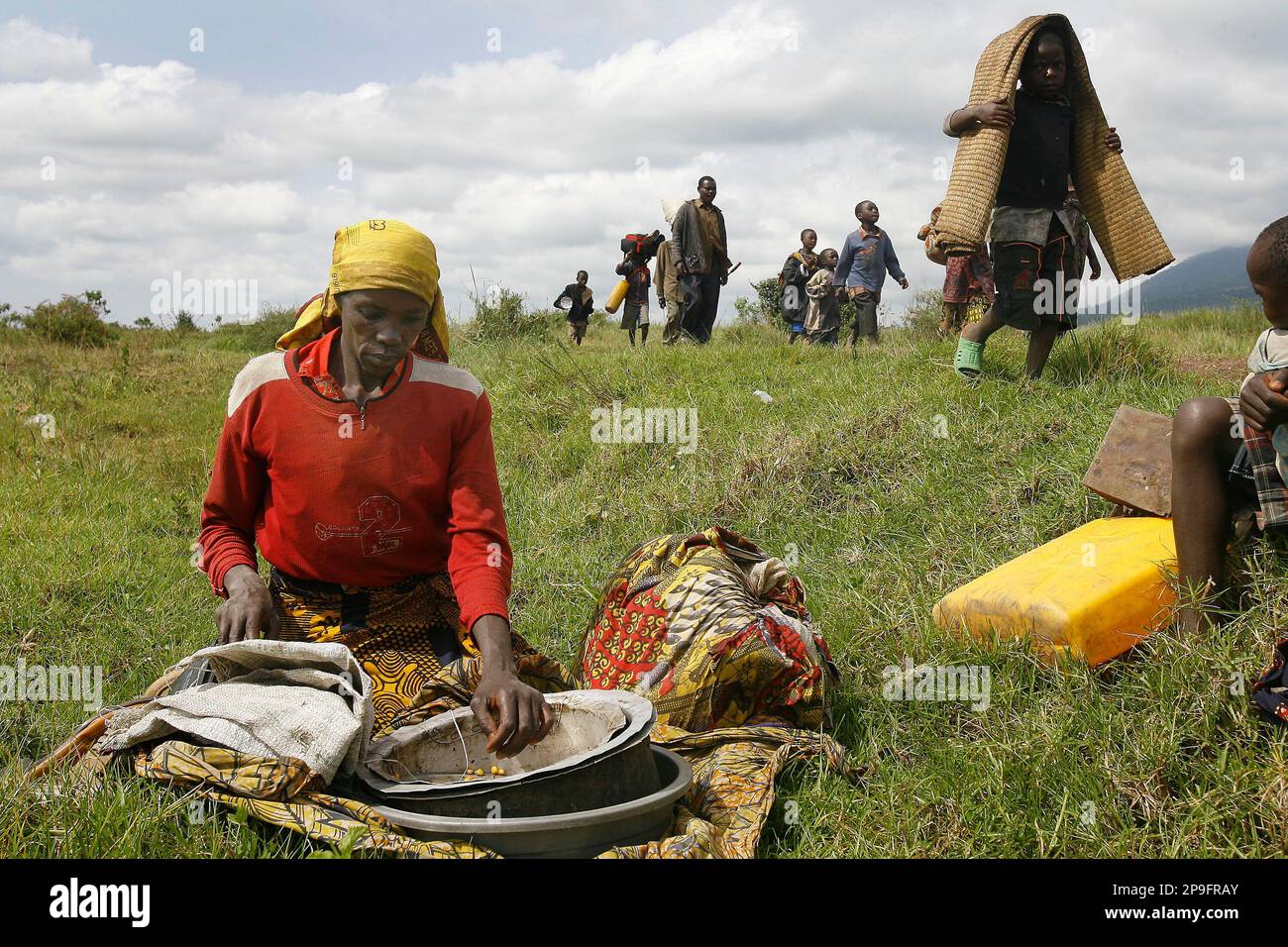 A woman stops to rest as thousands of displaced people walk along a ...