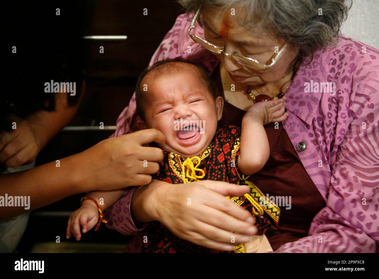 An unidentified person, only hand seen, comforts a crying three-month ...