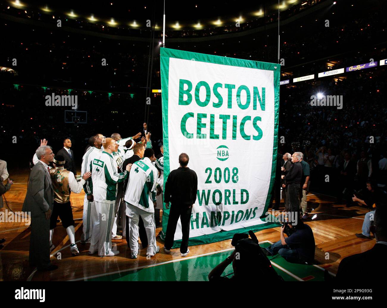 The Boston Celtics players and team personnel gather around to raise ...