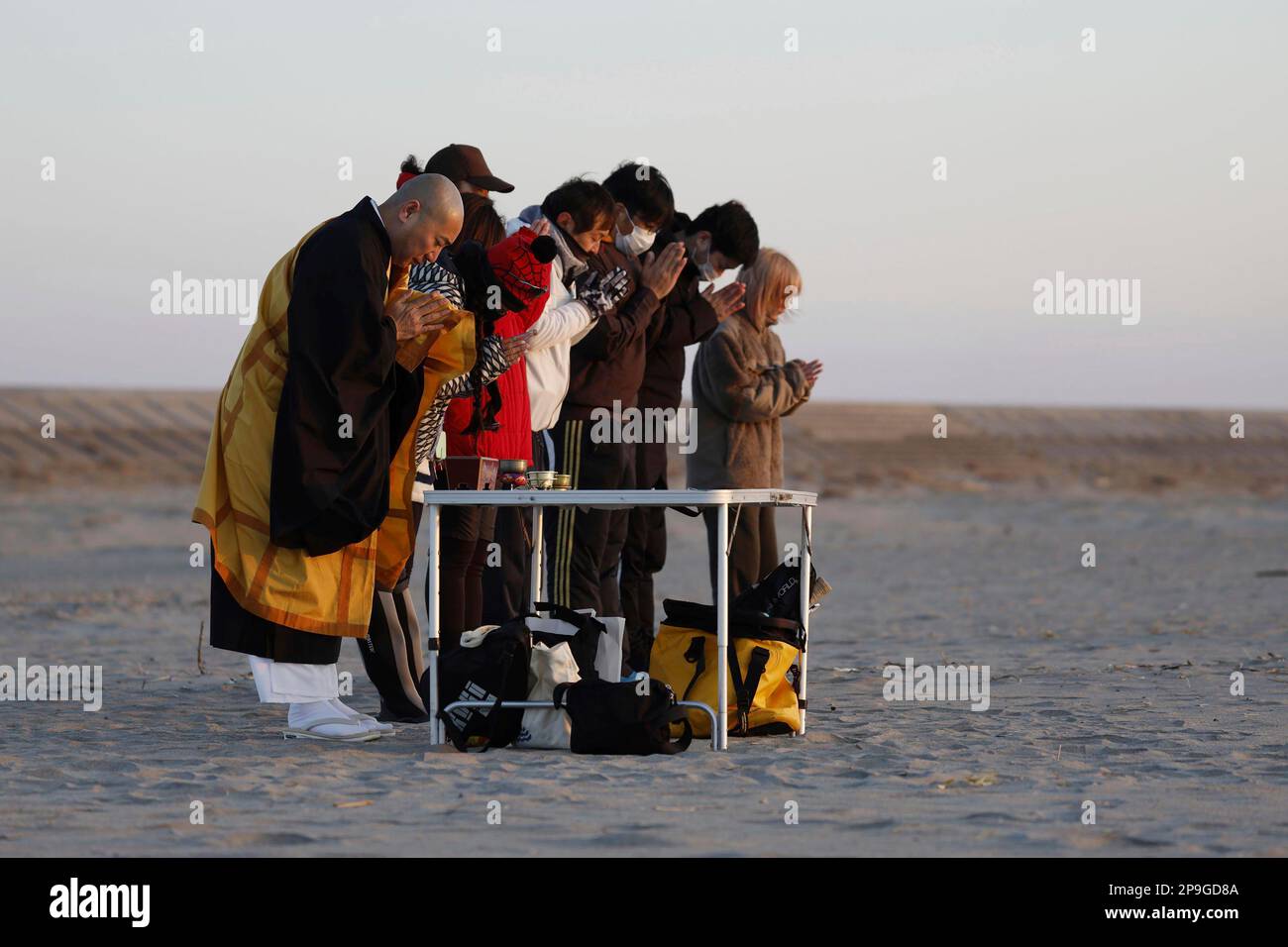 A monk and people offer prayers for the victims of the 2011 massive ...