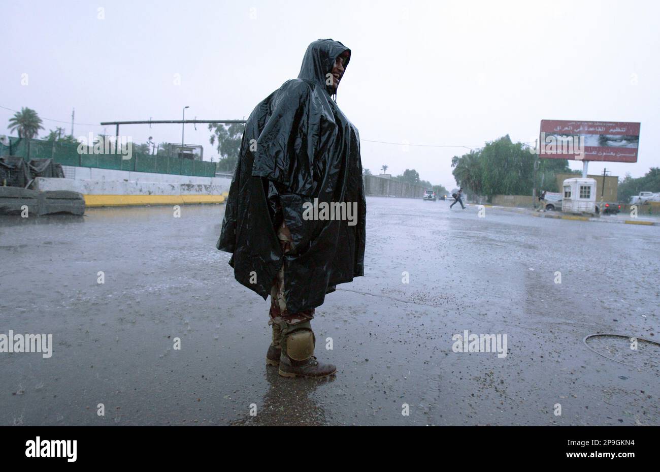 An Iraqi army soldier stands guard at a check point during a rainfall ...