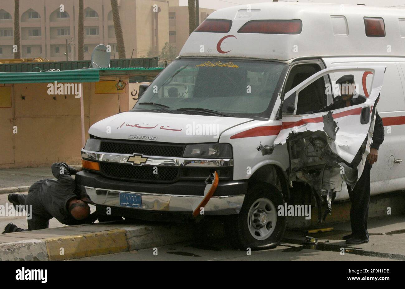 Iraqi Policemen inspect a damaged ambulance after it was hit by a ...