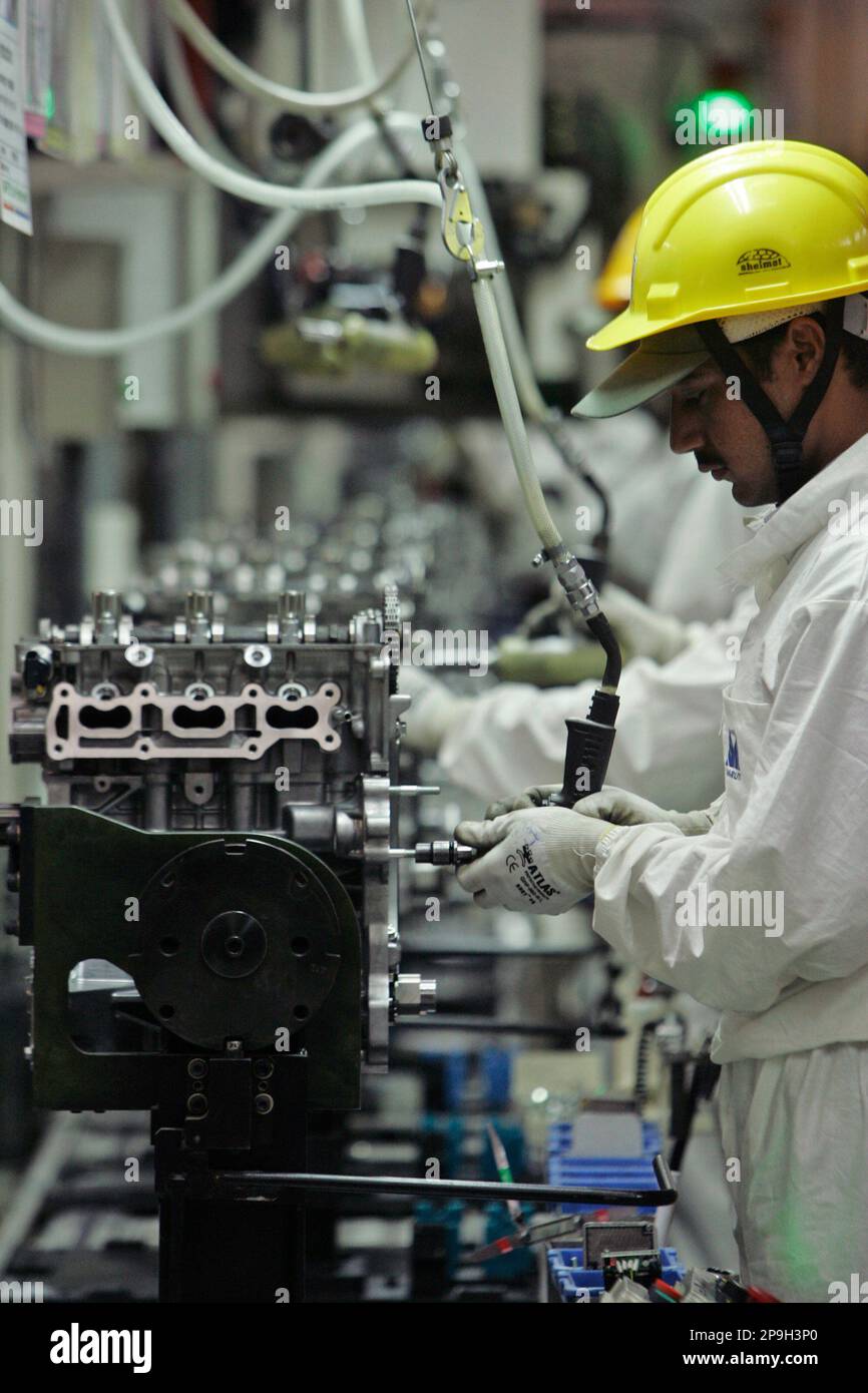 A worker assembles a semi complete engine at the assembly line of the ...