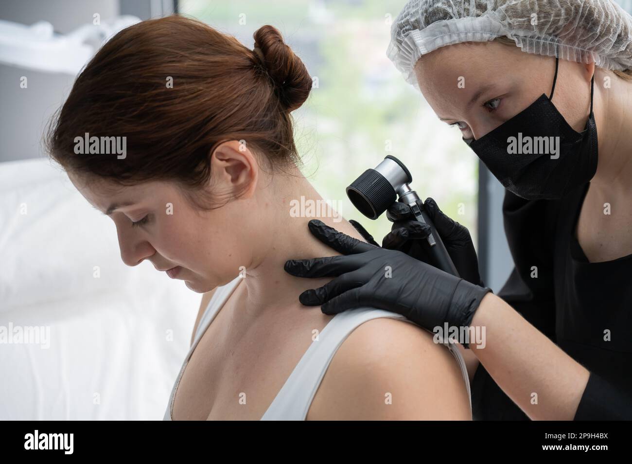 A dermatologist examines a patient's mole through a dermatoscope Stock ...