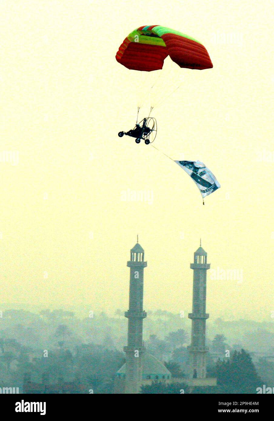 An Egyptian military motorized paraglider carries a poster showing late ...