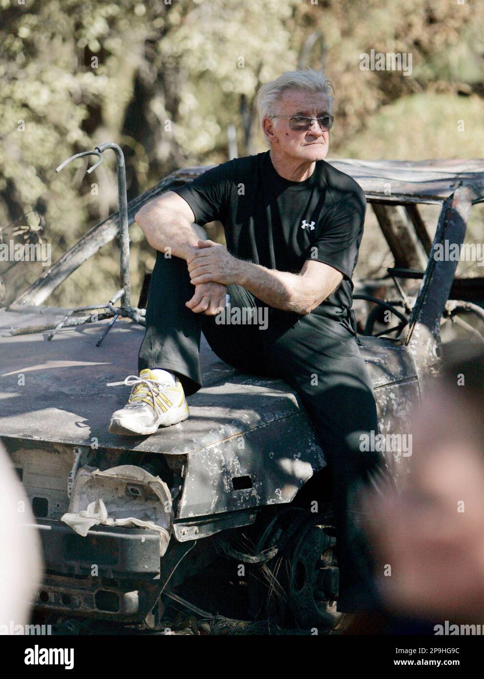 Monty Cox, whose home was destroyed, sits atop a neighbor's burned car ...
