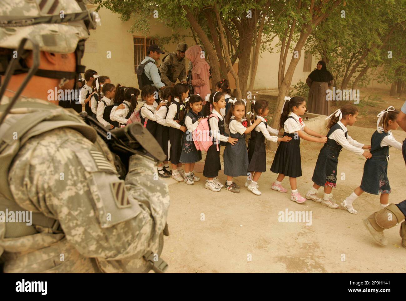 An American soldier watches over kids as troops visited a school to ...