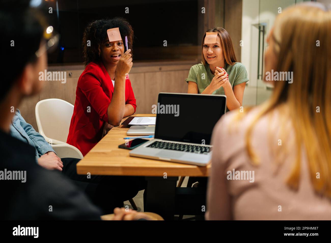 Friendly multiethnic startup team playing guessing game with sticky ...