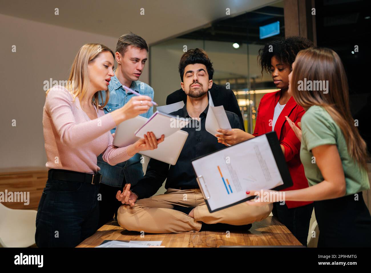 Portrait of calm male team leader sitting on office table in lotus ...