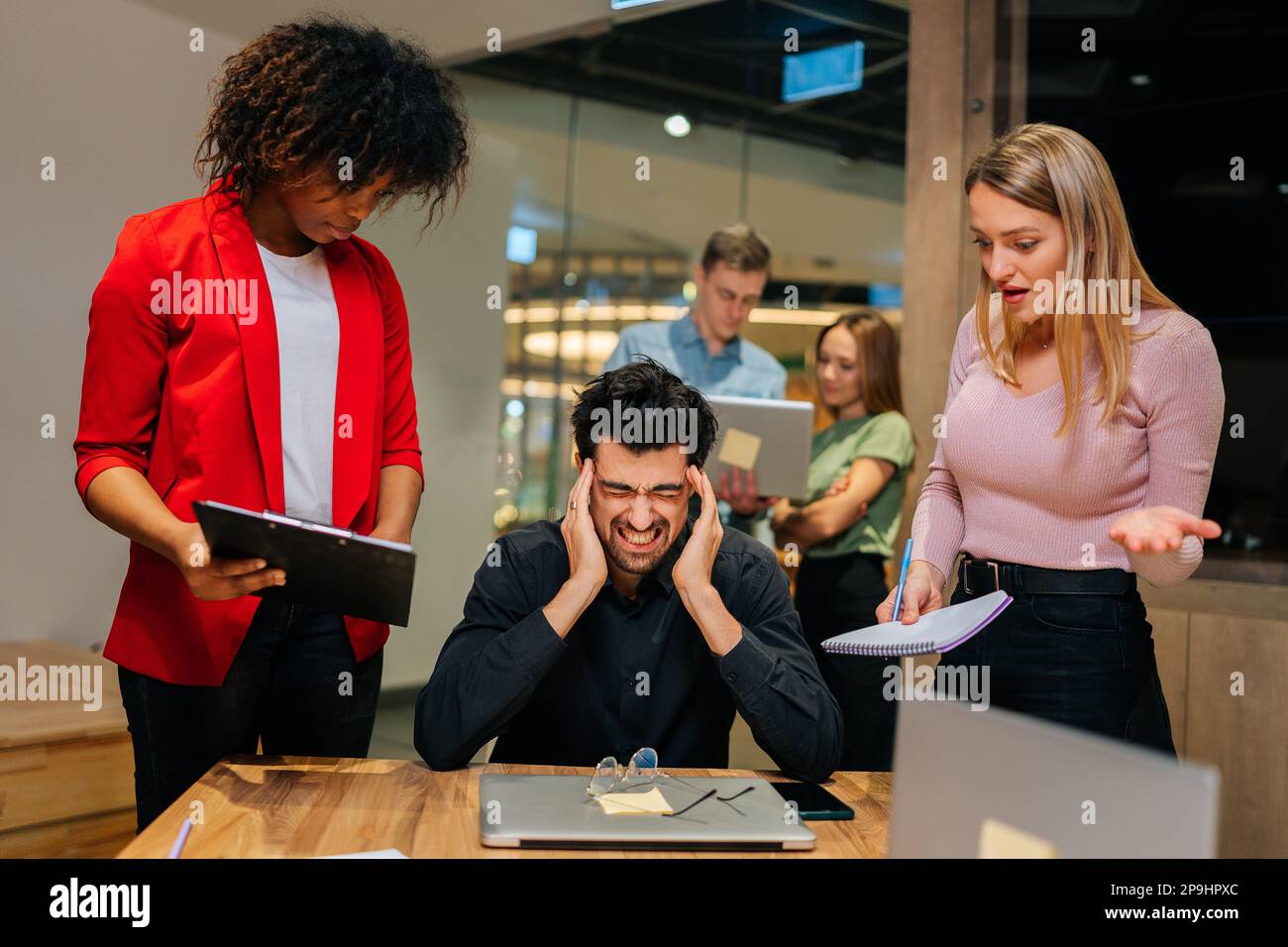 Portrait of overworked team leader under stress sitting at table with ...