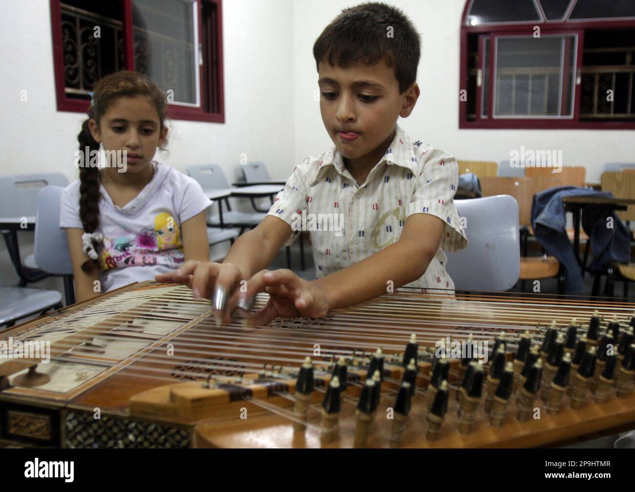 A Palestinian boy plays the kanoun, a traditional instrument used in ...