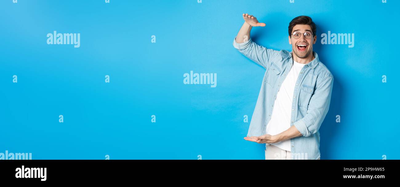 Happy man in glasses showing big size object, shaping large box ...