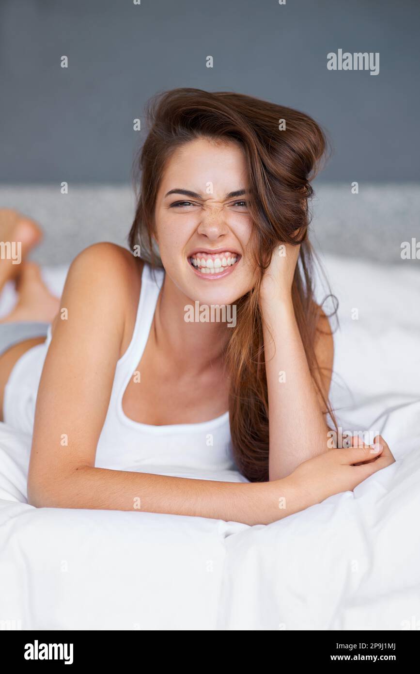 My silly morning face. A young woman pulling faces while lying in bed ...