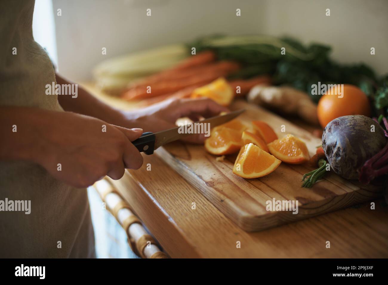 Getting a daily dose of vitamin c. a woman slicing oranges on a chopping board Stock Photo - Alamy