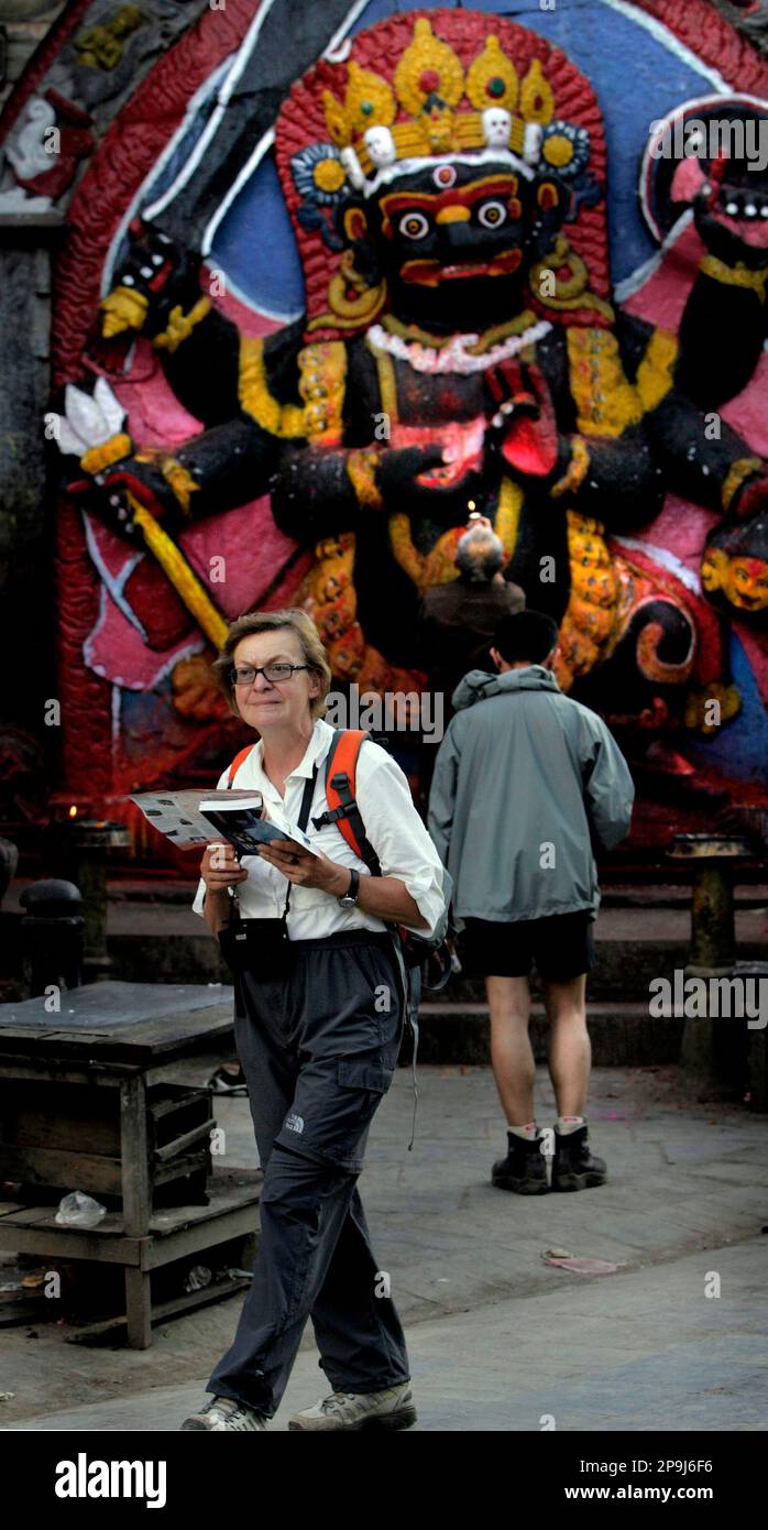 An unidentified foreign tourist walks past an idol of Hindu Goddess ...
