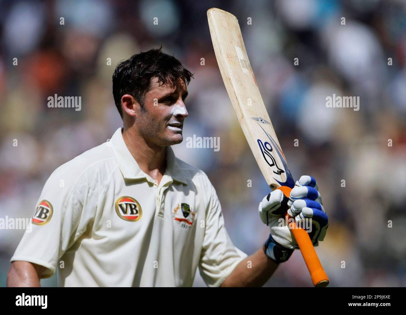 Australian cricket player Mike Hussey, left, raises his bat to ...