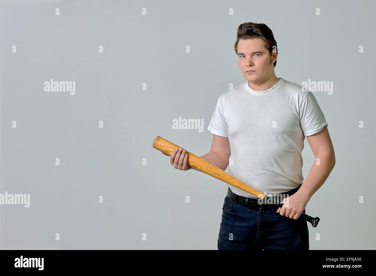 a man on a gray background holds a bat in his hands Stock Photo - Alamy