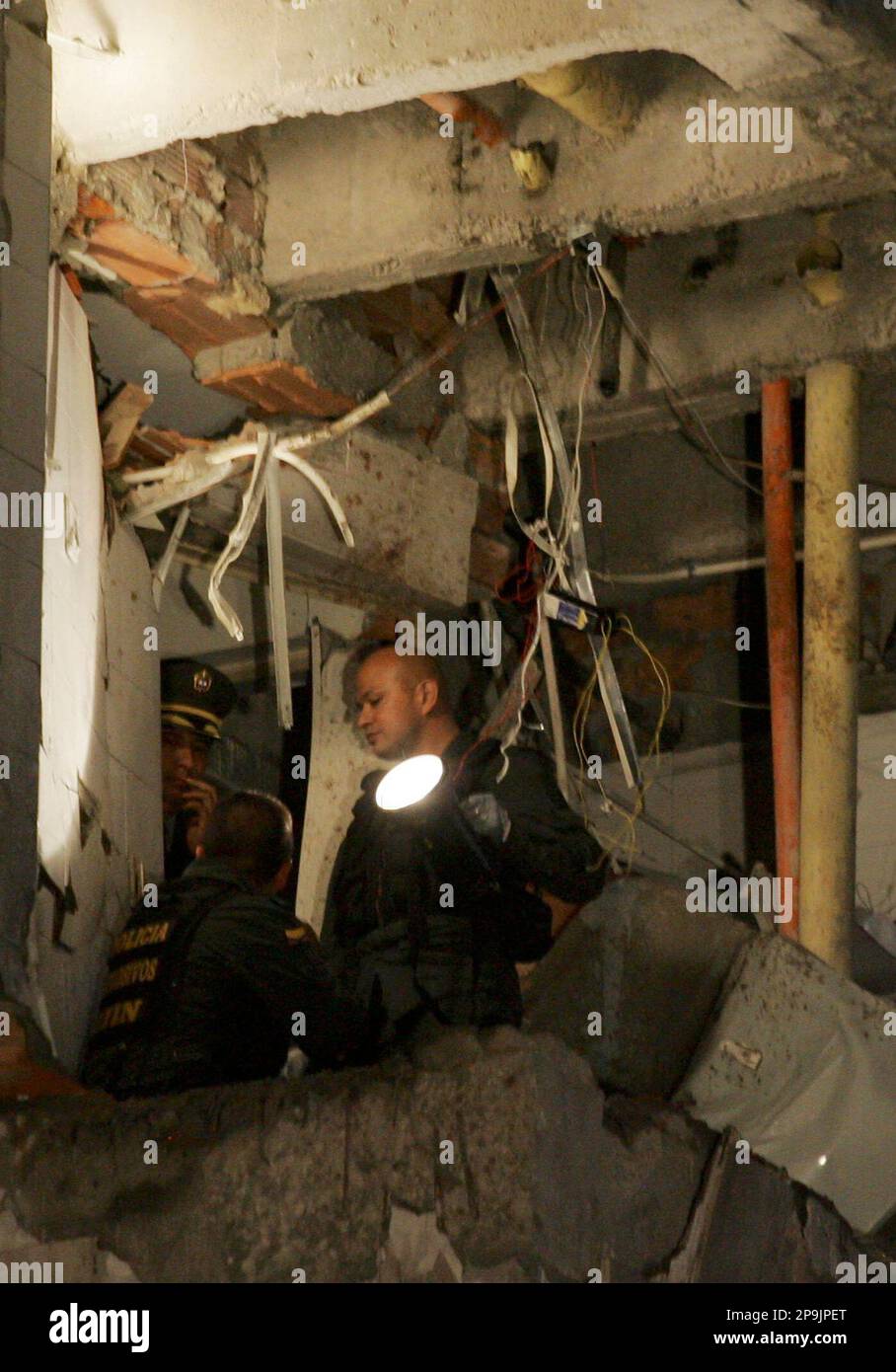 Police officers inspect the damage caused by an explosion at a building ...