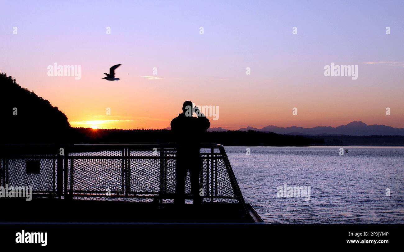 A ferry commuter on the auto ferry Hyak takes a photo of the sunset ...