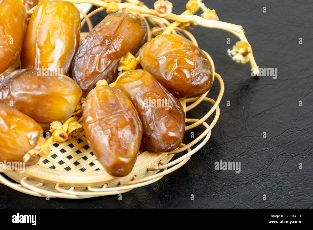 Close-up of Algerian royal dates on a wooden plate on a black ...