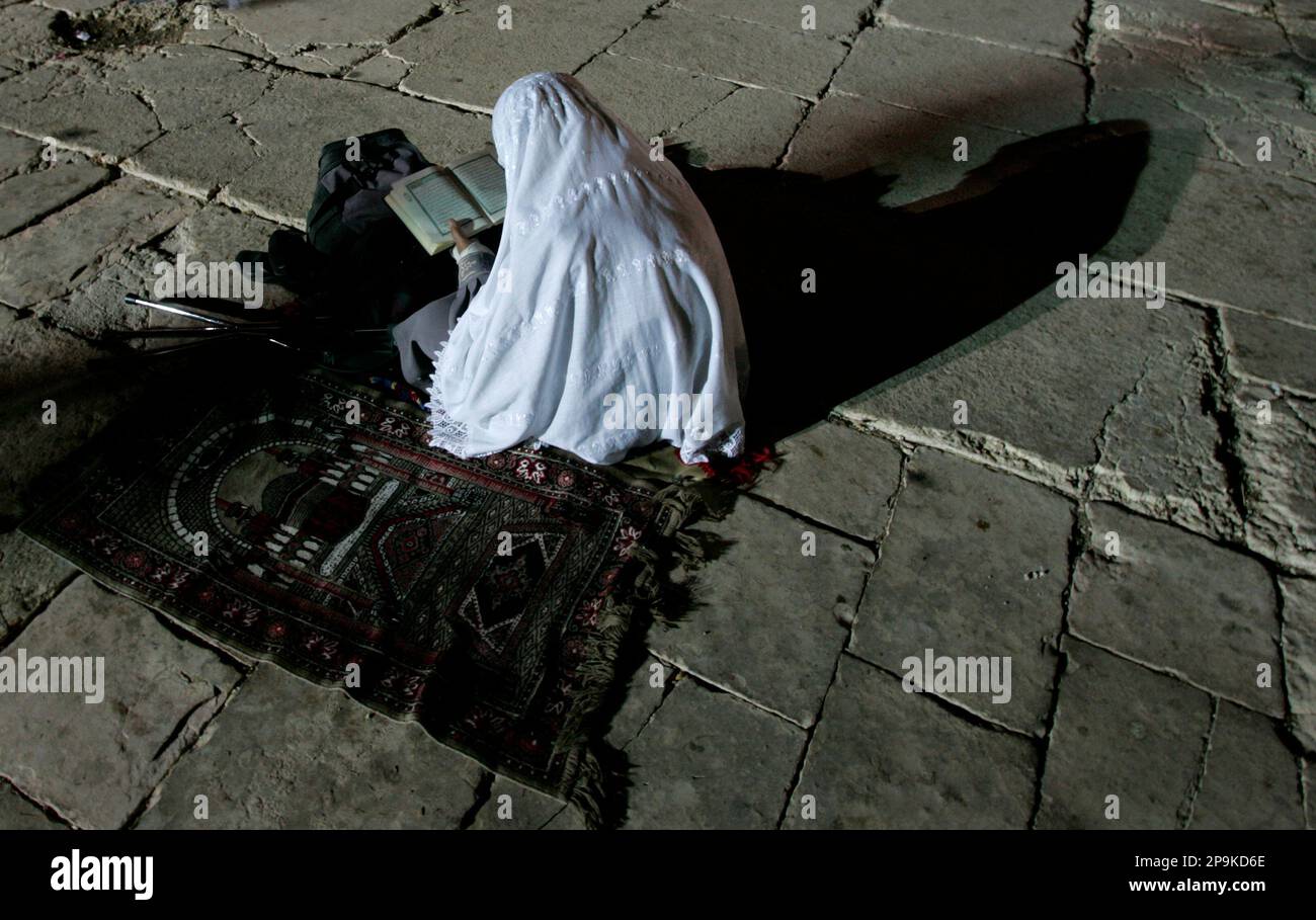 A Palestinian Muslim worshiper sits on the ground reading verses of ...