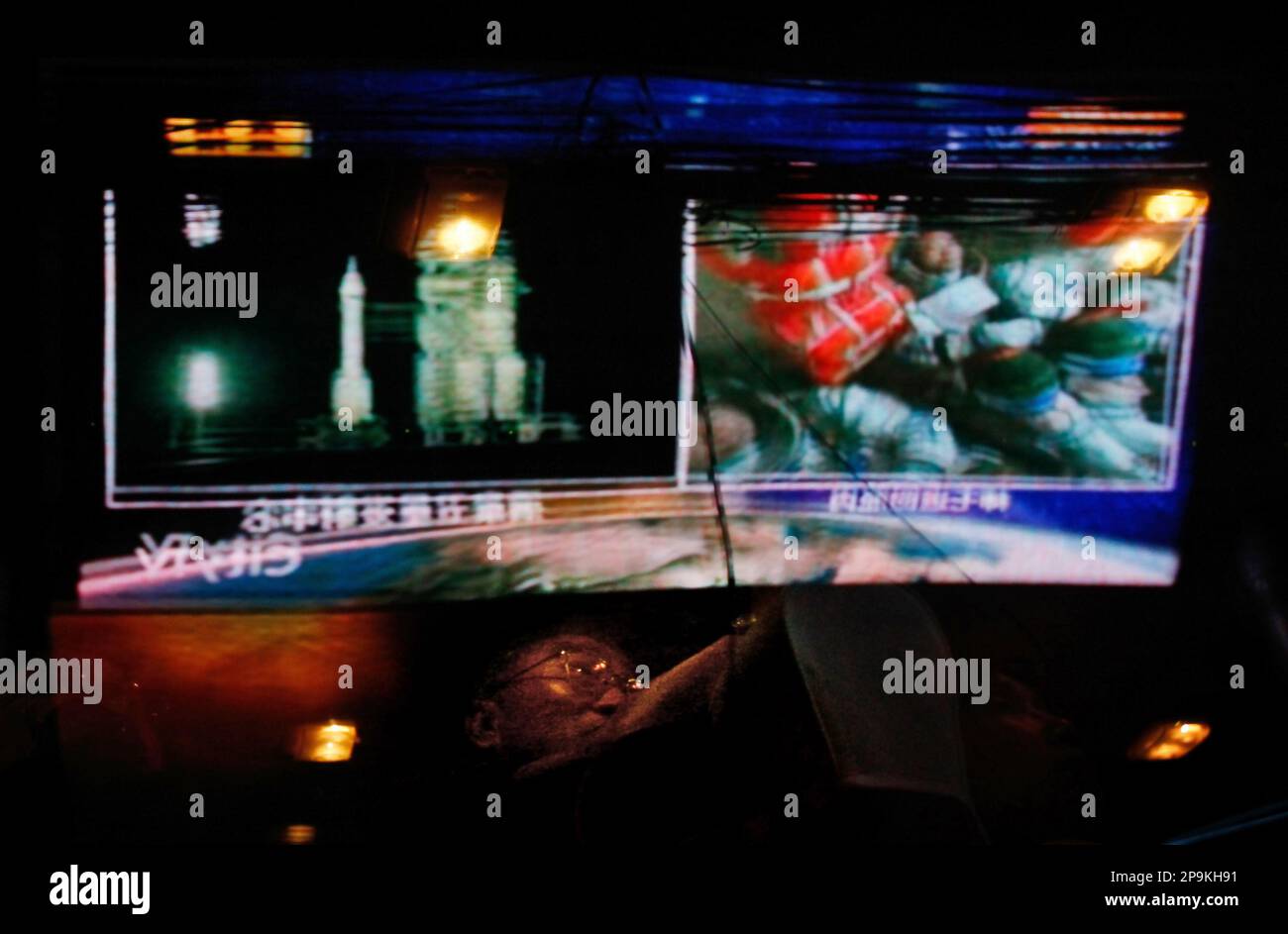 A passenger inside a bus watches the Shenzhou 7 manned space craft launched from the Jiuquan ...